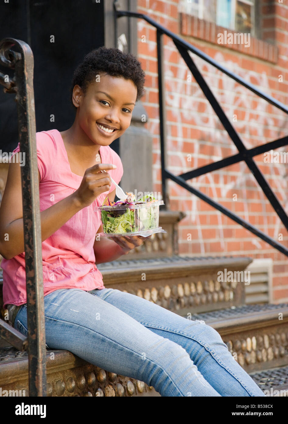African woman sitting on steps eating salad Stock Photo - Alamy