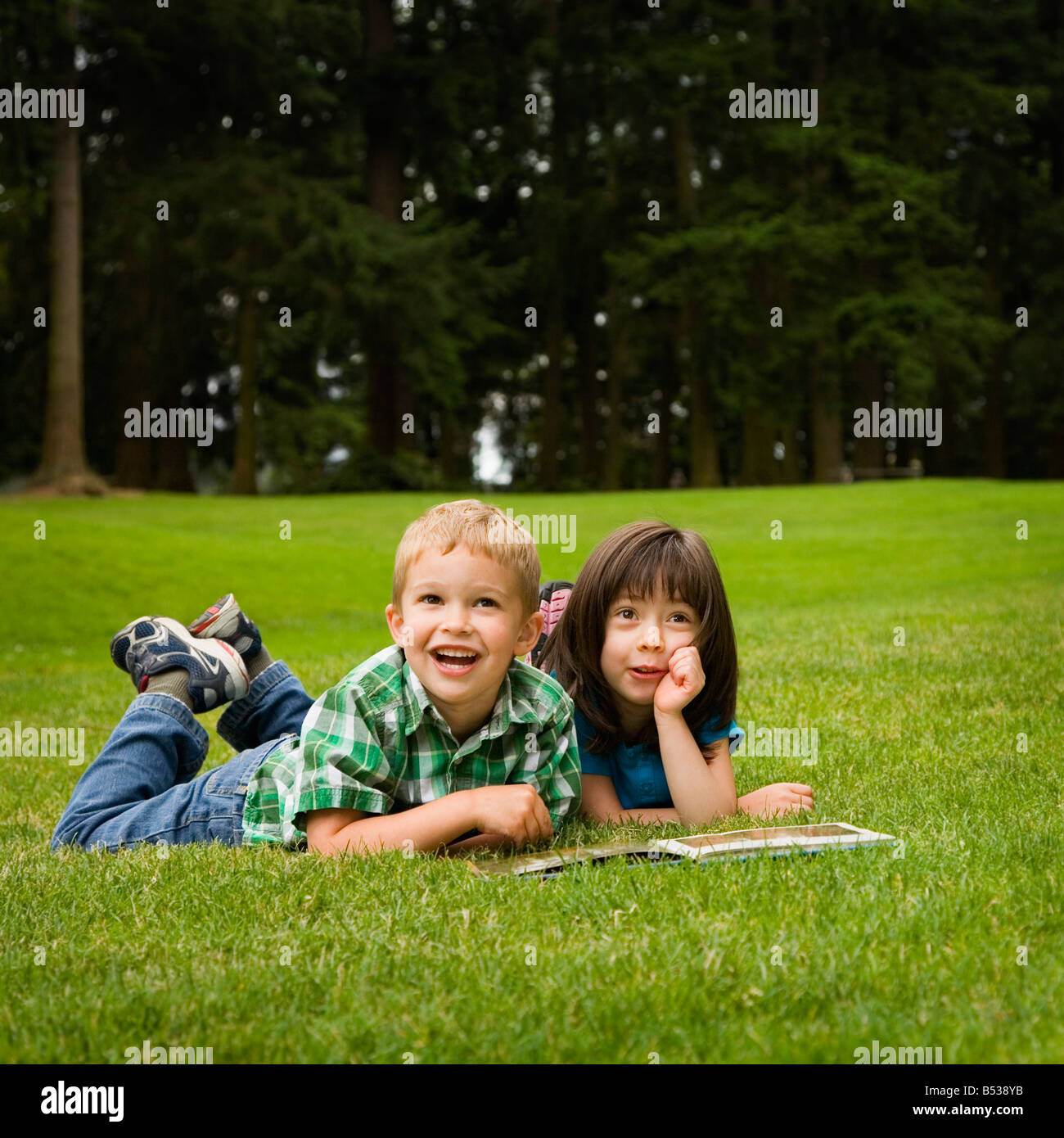 Brother and sister reading story book in park Stock Photo - Alamy