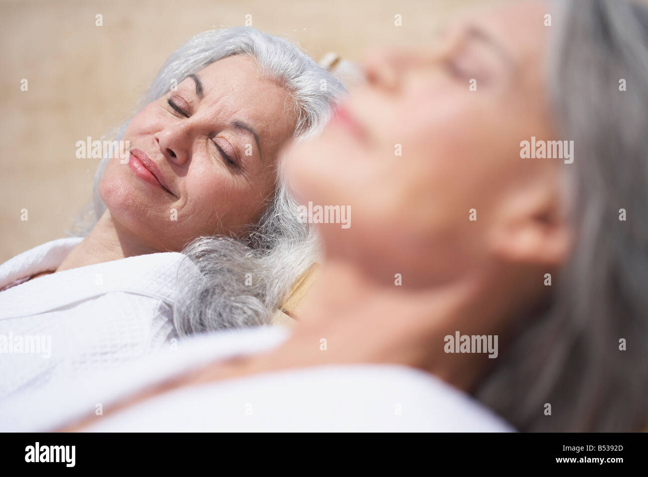 Friends sleeping on lounge chairs at resort Stock Photo - Alamy