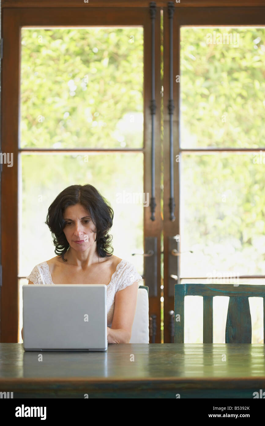 Confident Middle Eastern woman typing on laptop in dining room Stock ...