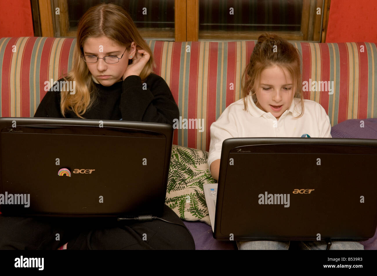 two welsh girls, sisters school children using laptop computers to send ...