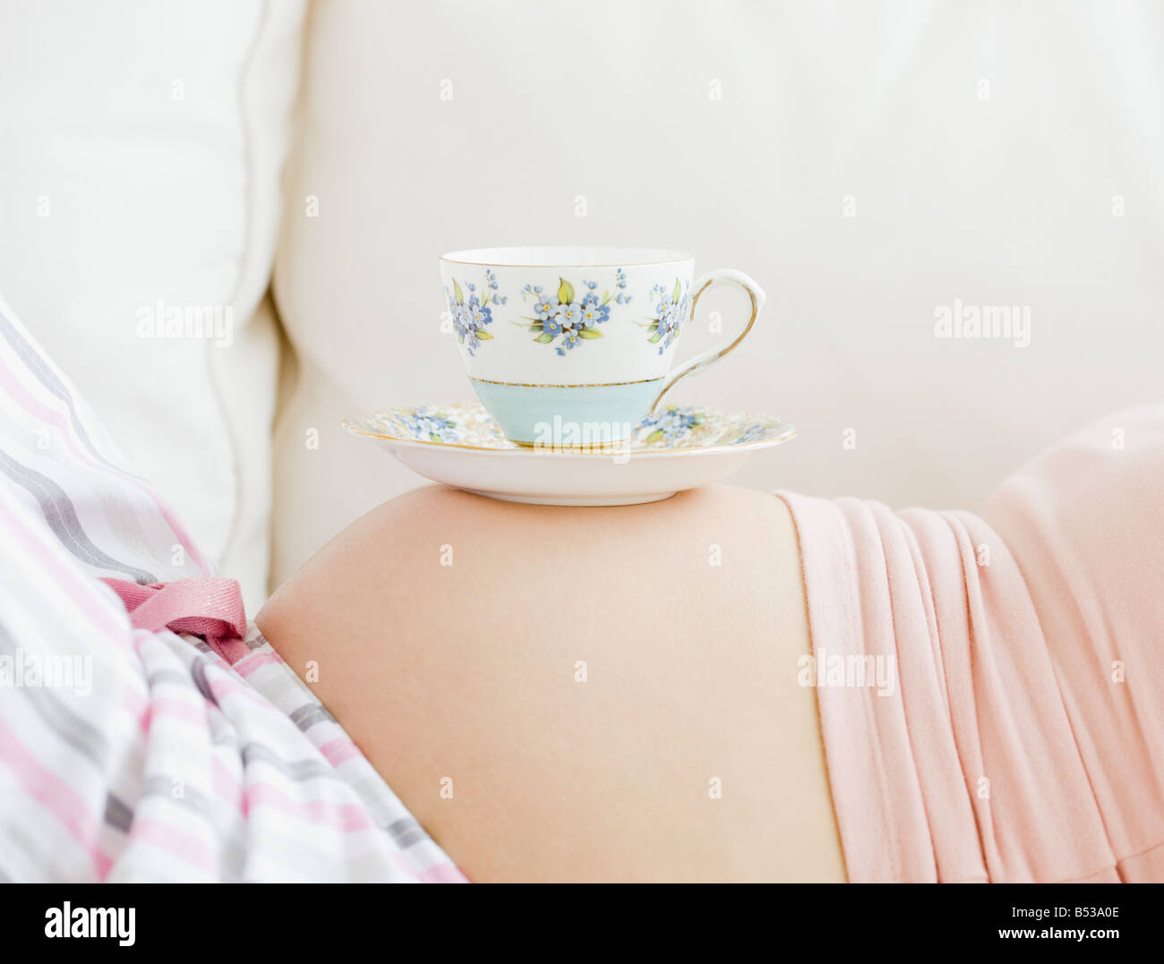 Pregnant Asian woman balancing tea cup on stomach Stock Photo - Alamy