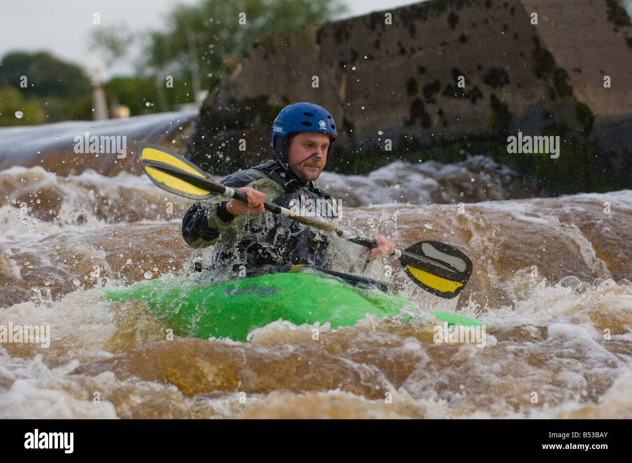 Caucasian male kayaker in a green kayak in fast flowing white water ...