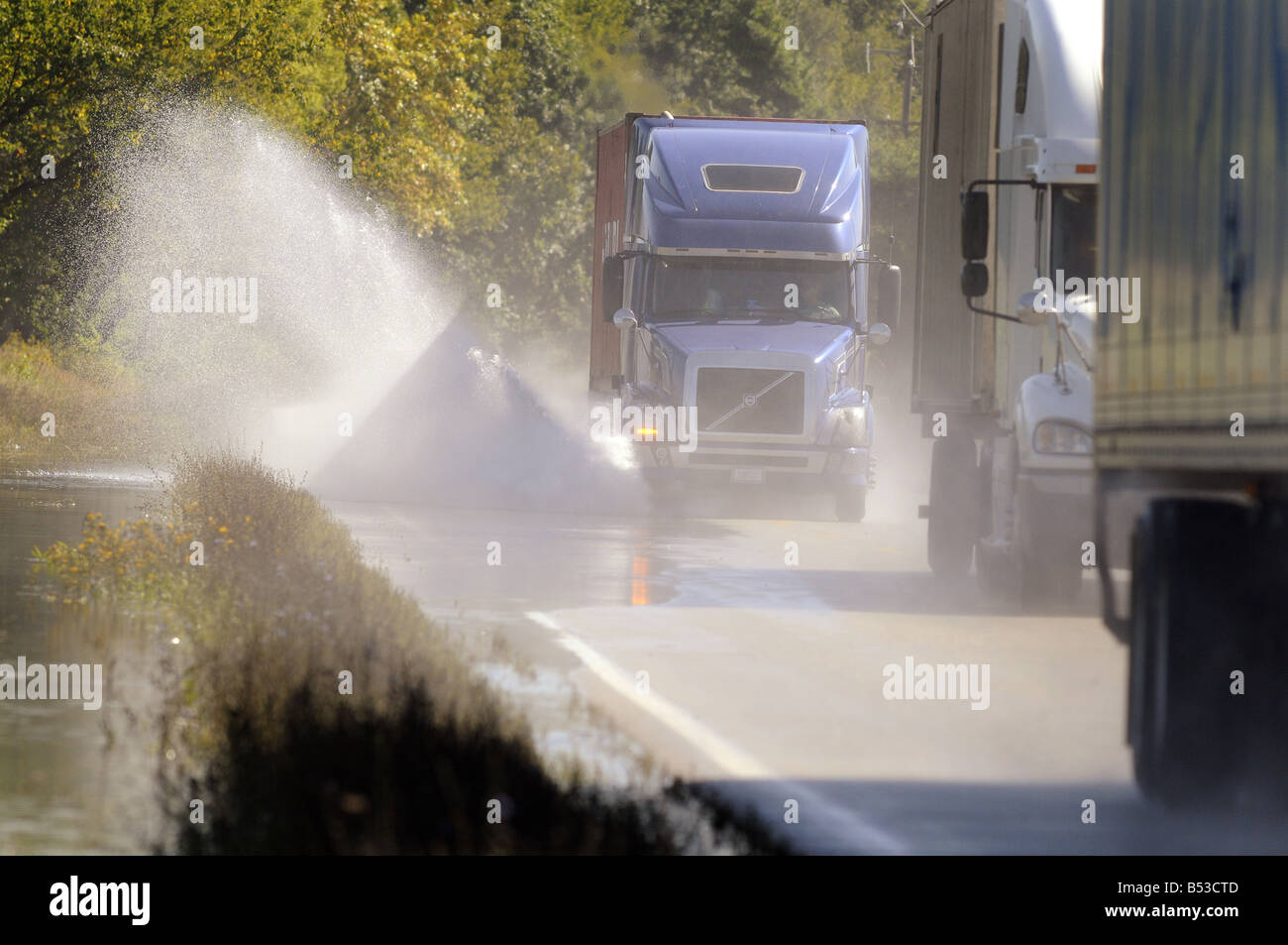 A line of trucks run into high standing water on a rural road Stock ...