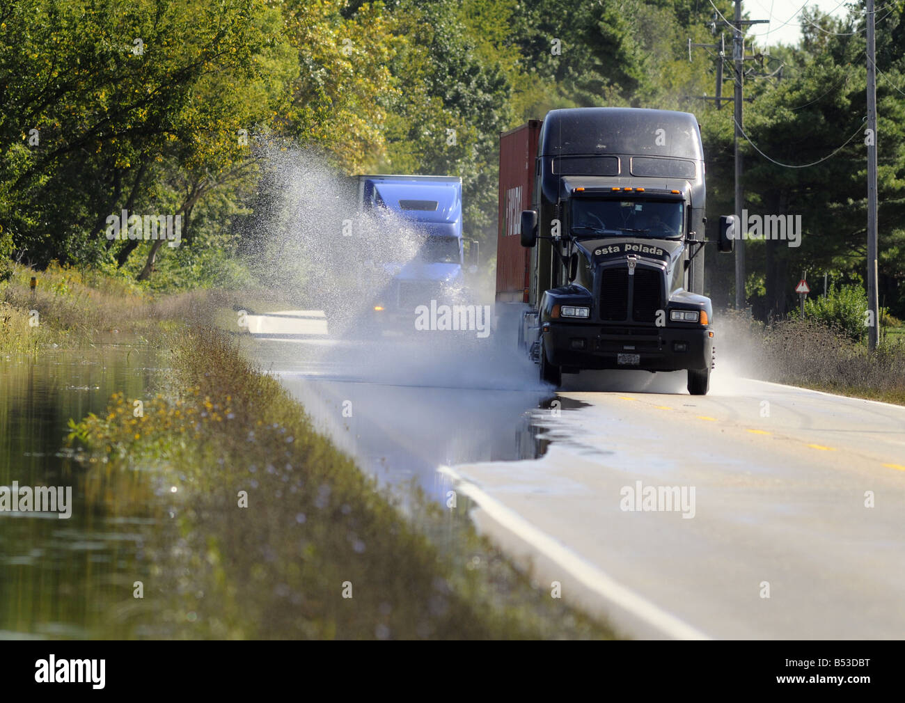 A line of trucks run into high standing water on a rural road Stock ...