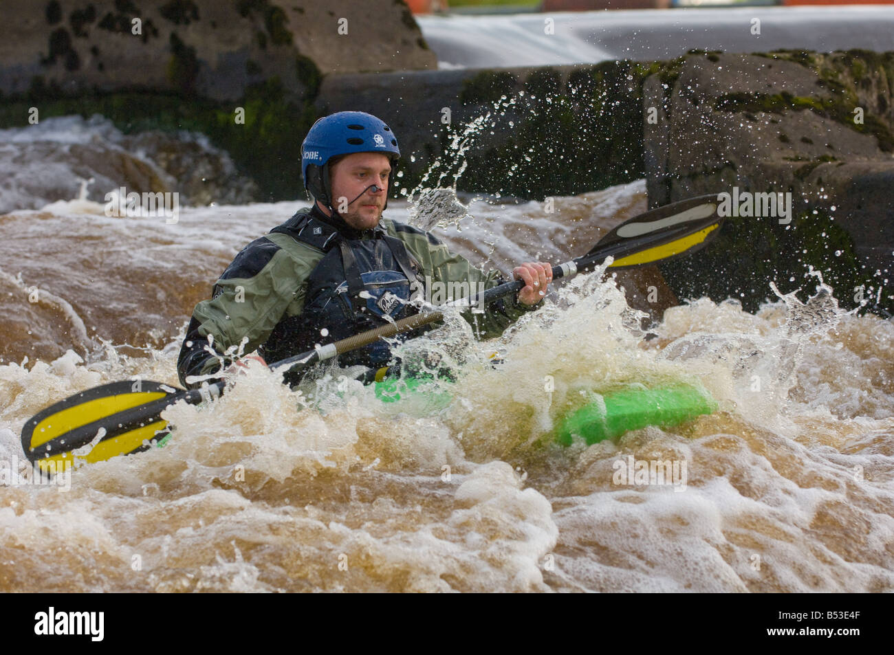 Caucasian male kayaker in a green kayak in fast flowing white water ...