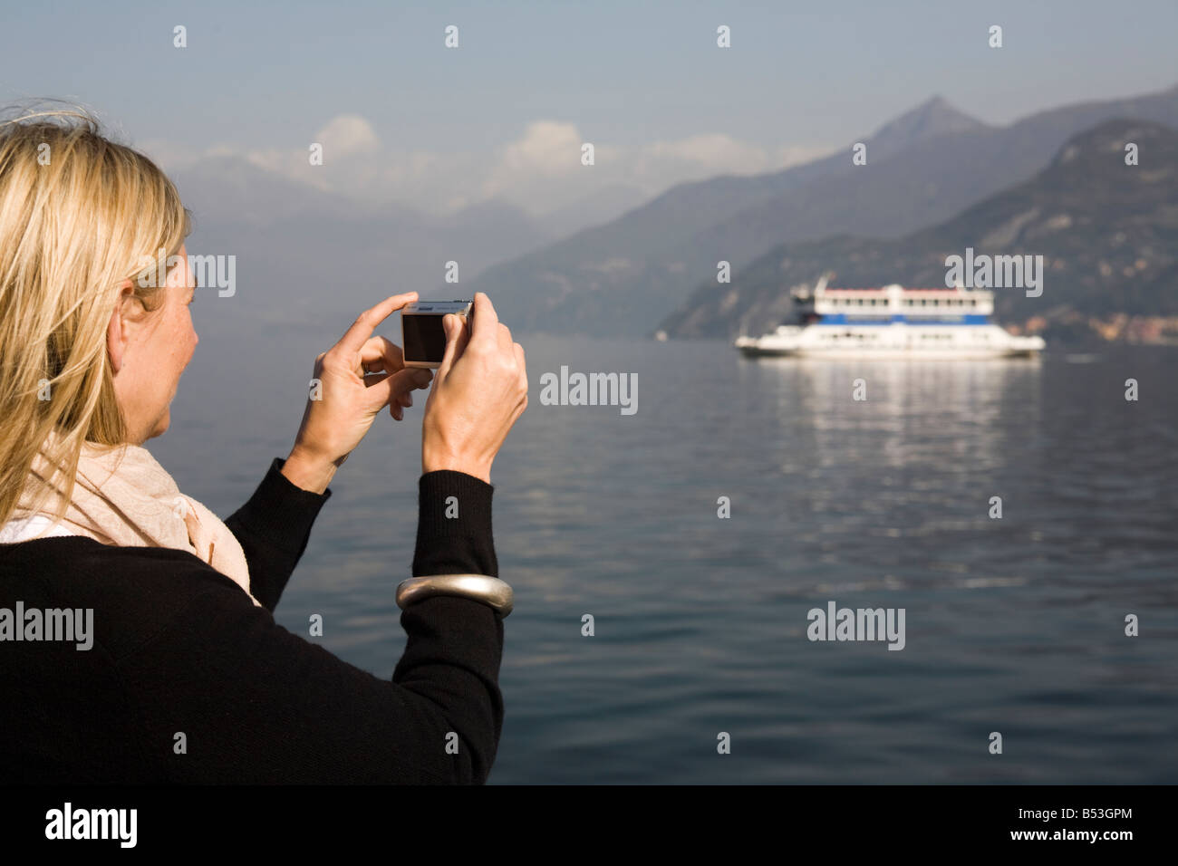 Woman shooting the approaching peninsula of Bellagio on Lake Como ...