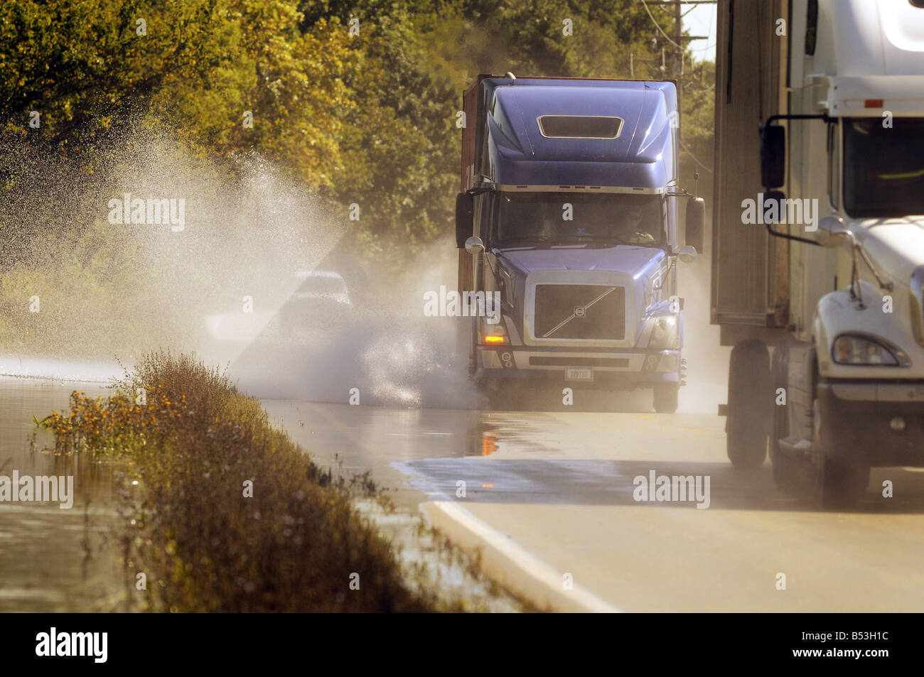 A line of trucks run into high standing water on a rural road Stock ...