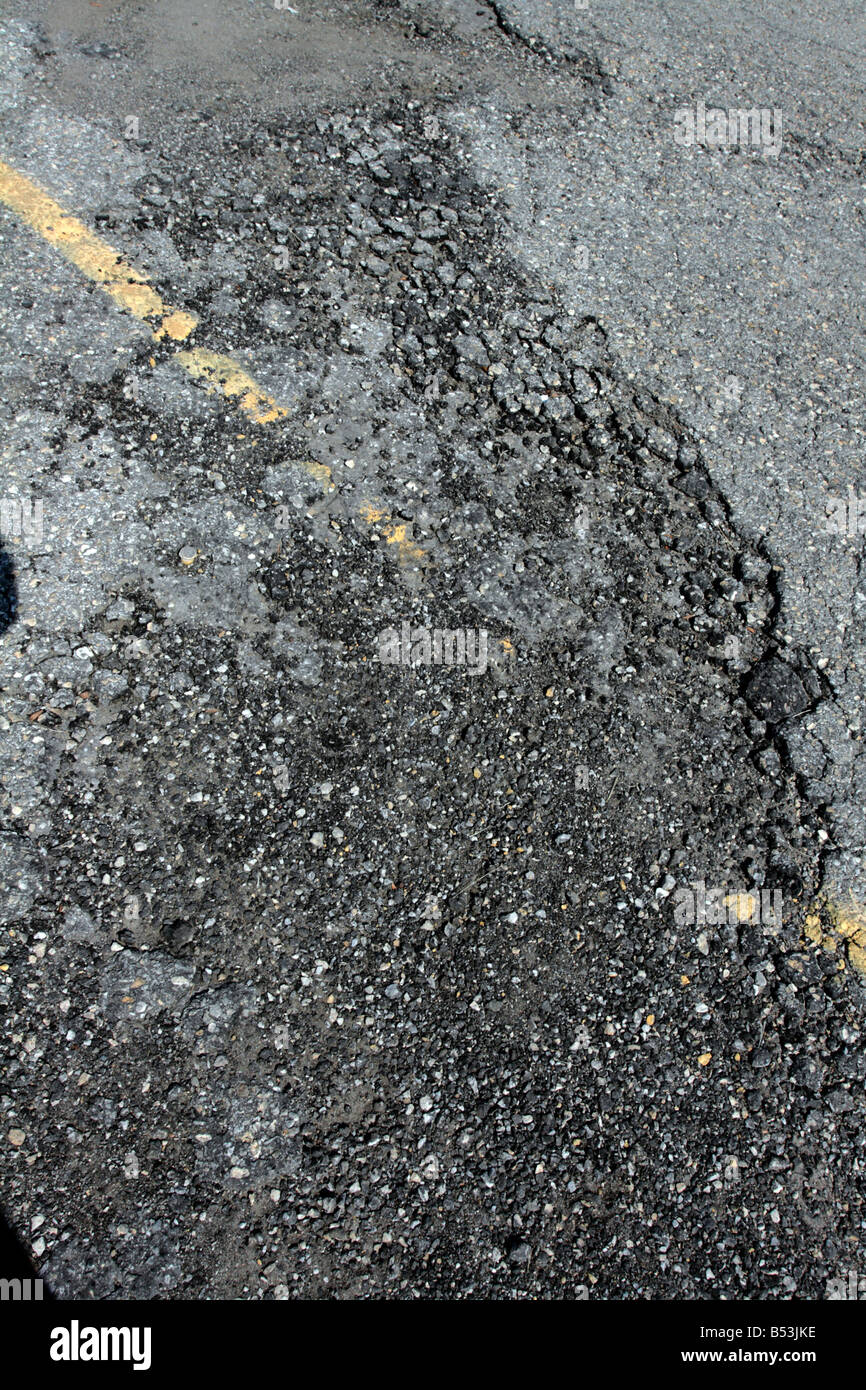 Crumbling broken asphalt surface with yellow line Stock Photo - Alamy