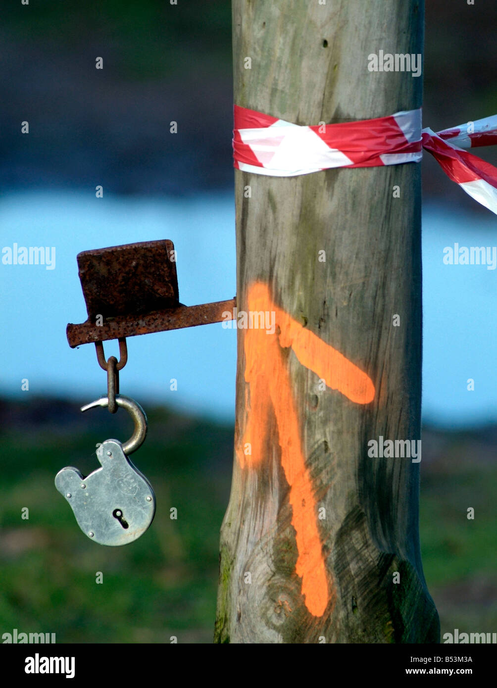 open metal padlock hanging from gate post with direction arrow painted ...
