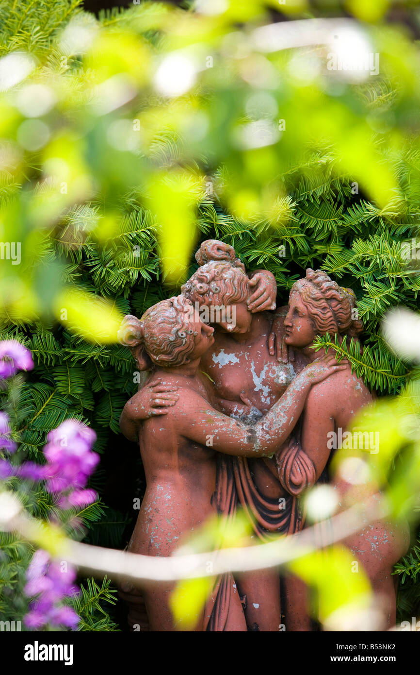 Terracotta statue of three ladies by a yew hedge Stock Photo - Alamy