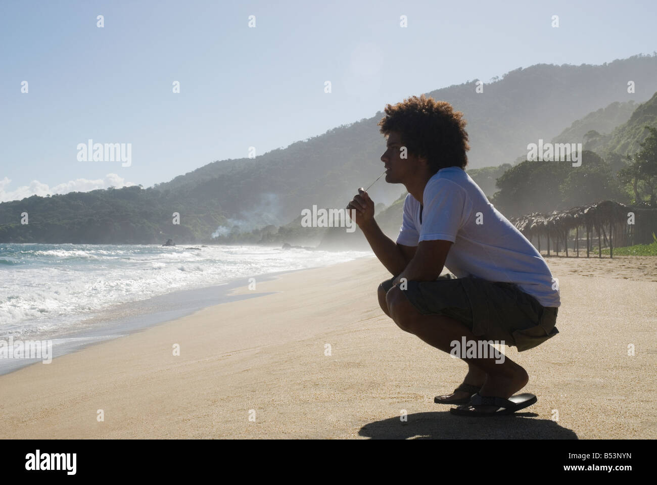 African man crouching at beach Stock Photo - Alamy