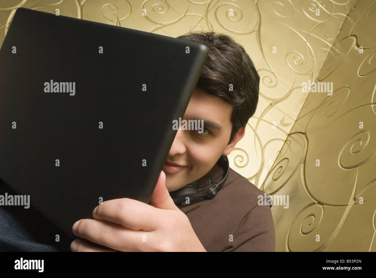 Hispanic man hiding behind laptop Stock Photo - Alamy