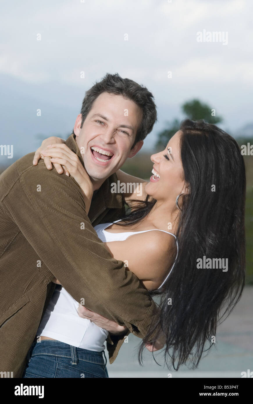Laughing Hispanic couple hugging Stock Photo - Alamy