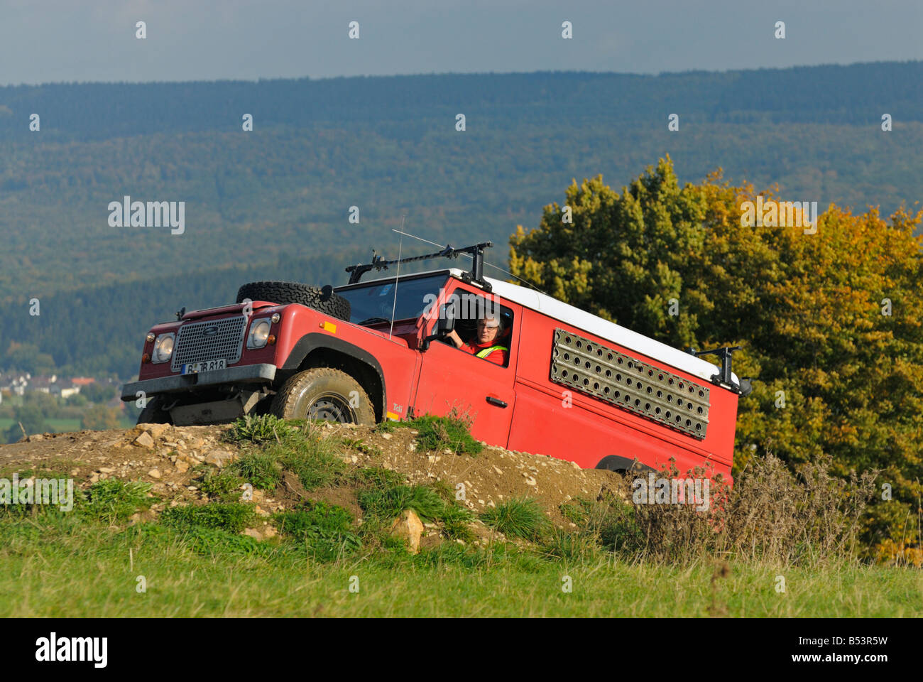 Red 1990s Land Rover Defender 110 TDI 300 hardtop on a forest track in ...