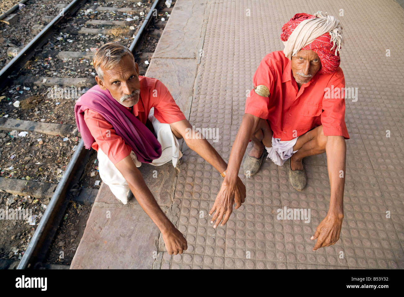Two station porters squatting on the platform, Sawai Madhopur station ...