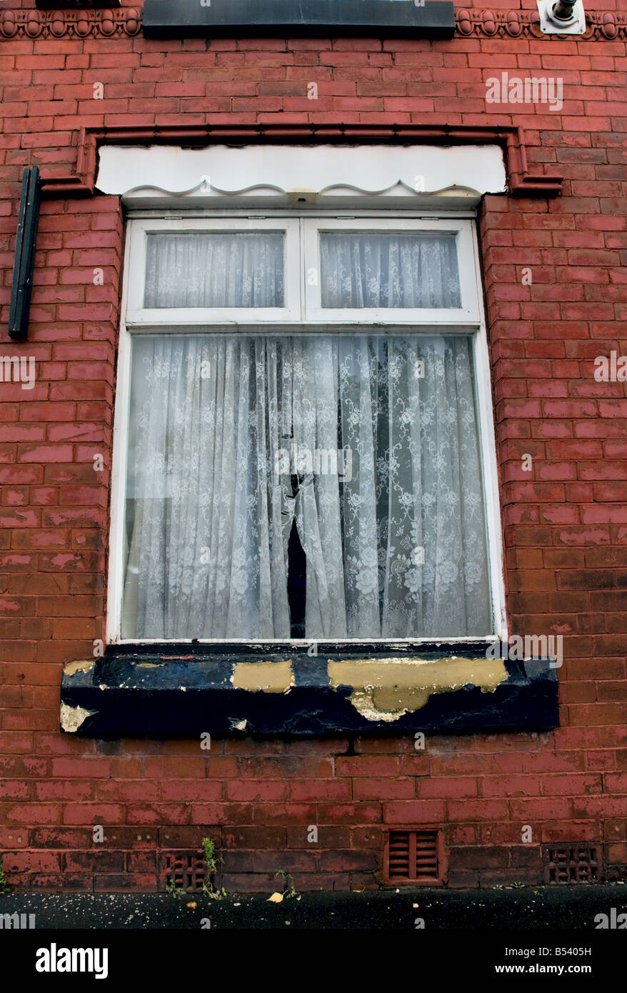 A window with tattered net curtain in shabby old Victorian terraced ...