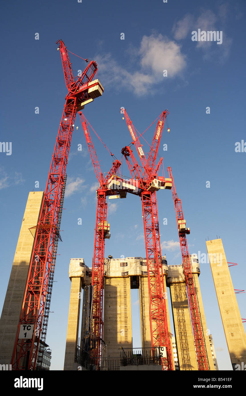 4 tower cranes against a blue sky with the lift shafts and stair cases ...