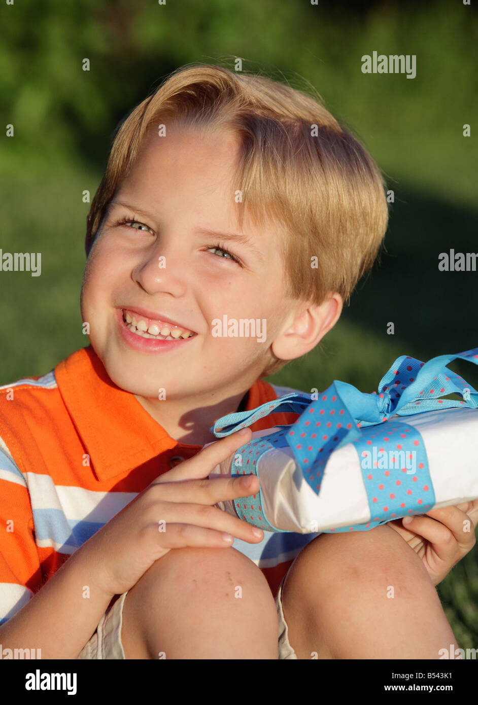 happy young boy holding wrapped gift outdoors Stock Photo - Alamy