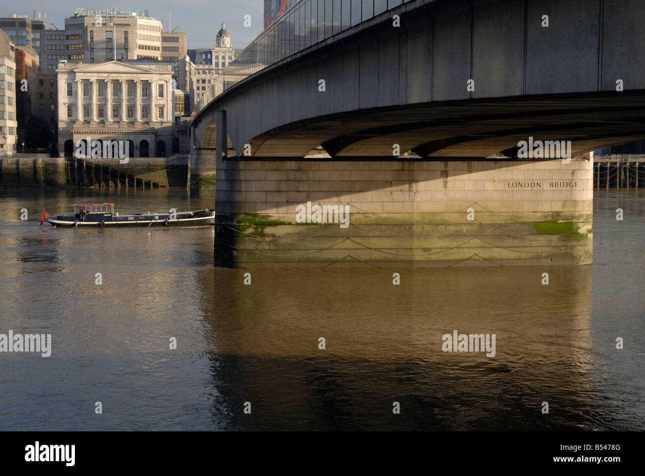 London Bridge viewed from below with barge passing, City of London. The ...