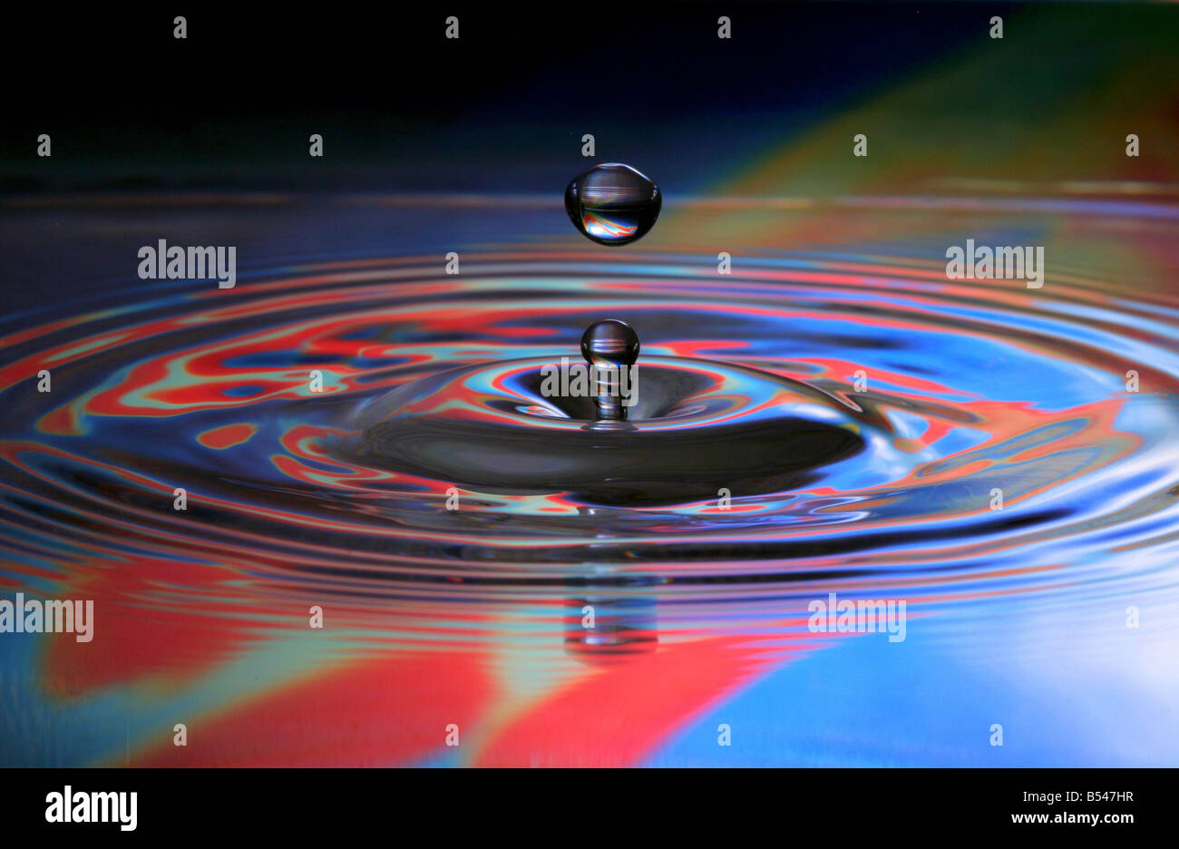 A water drop on a colorful reflection Stock Photo - Alamy