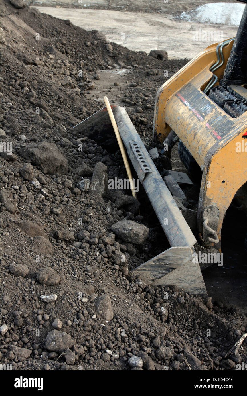 Dirt pile and tools with small loader bucket digging in Stock Photo - Alamy