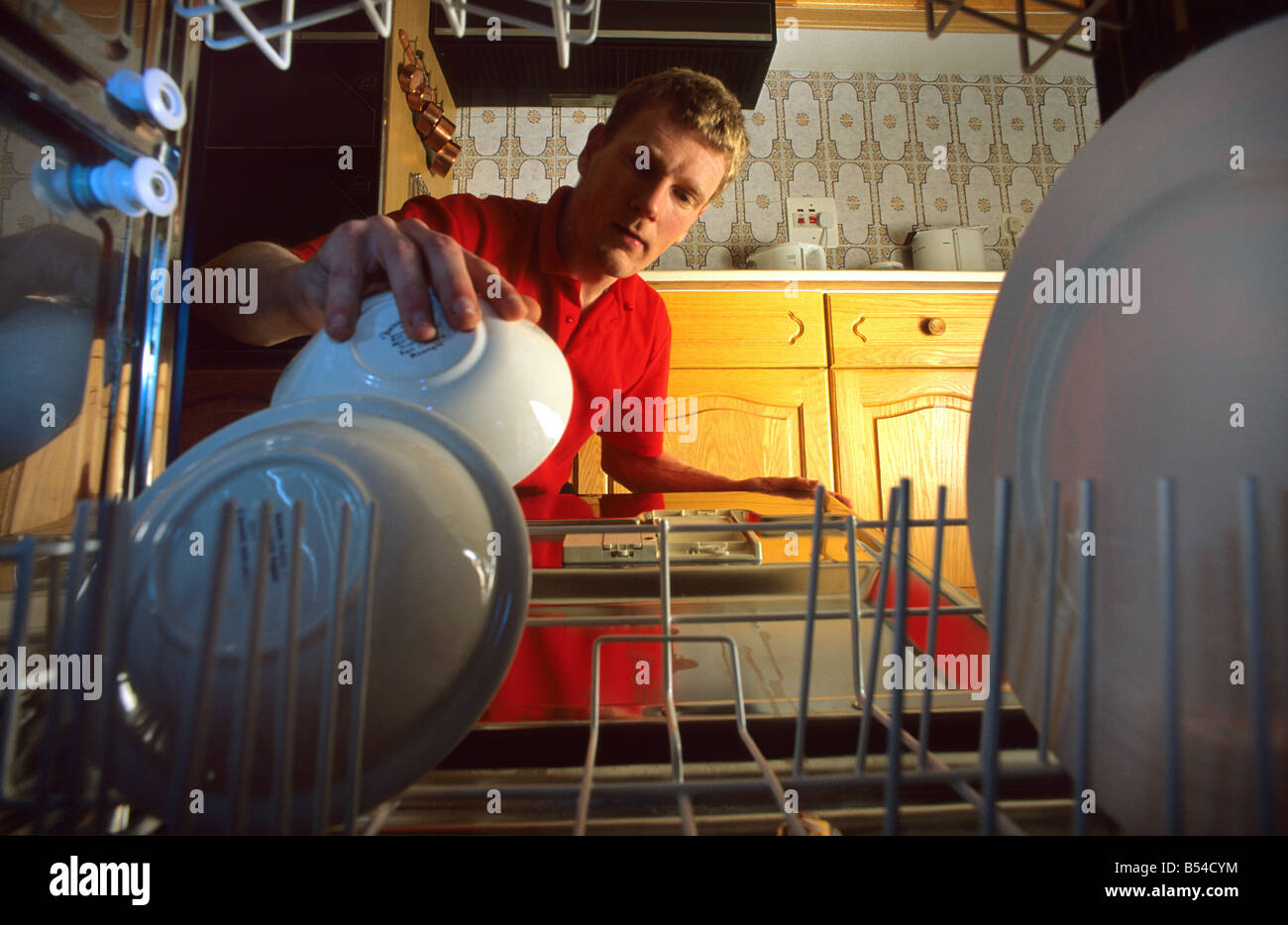 man loading dishwasher in kitchen with washing up Stock Photo - Alamy