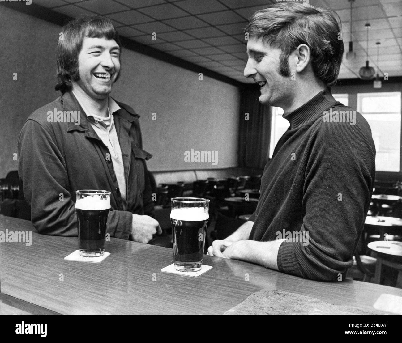 Two men have a pint of beer and a gossip at the bar Stock Photo - Alamy