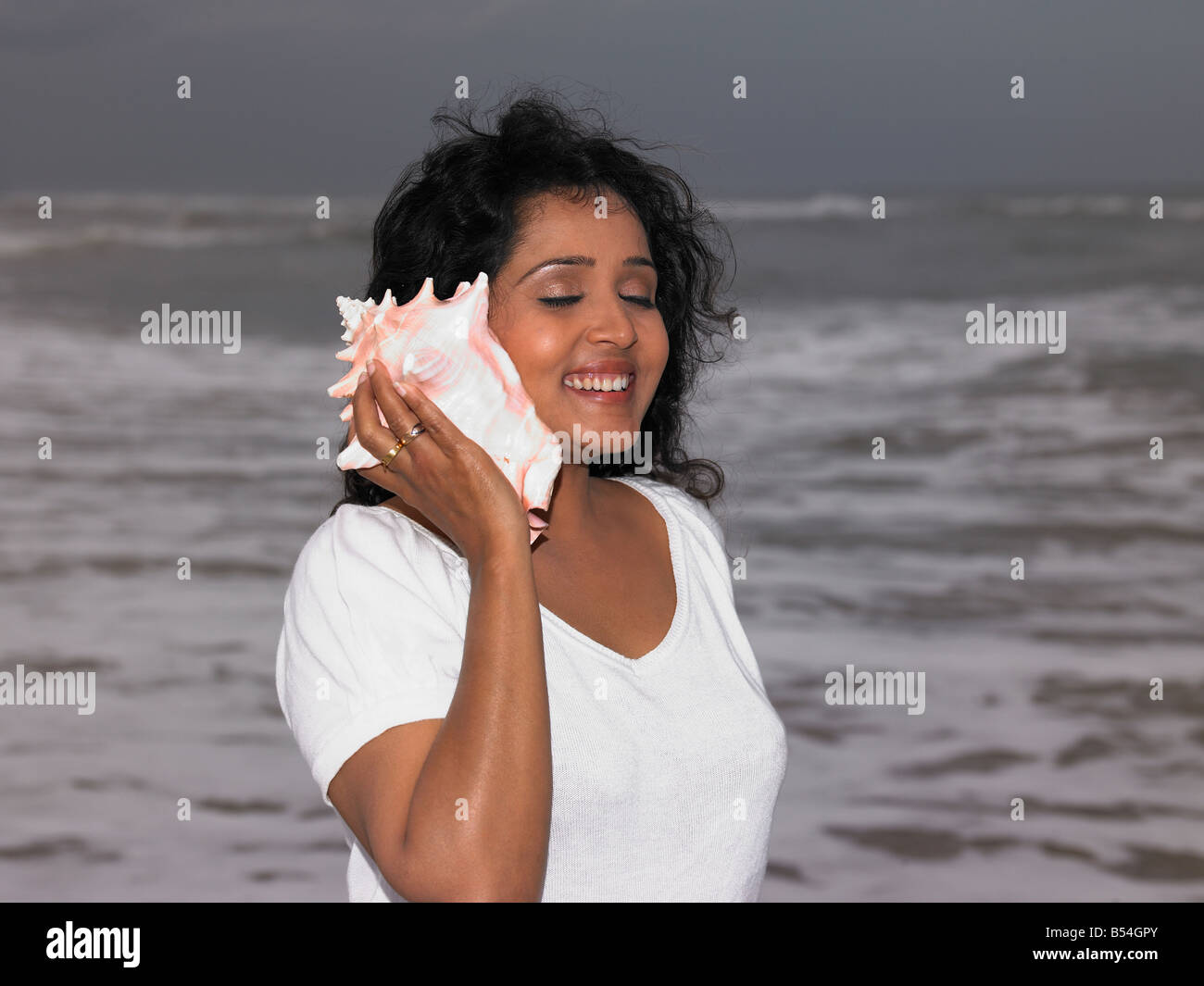 Woman holding conch shell ear hi-res stock photography and images - Alamy