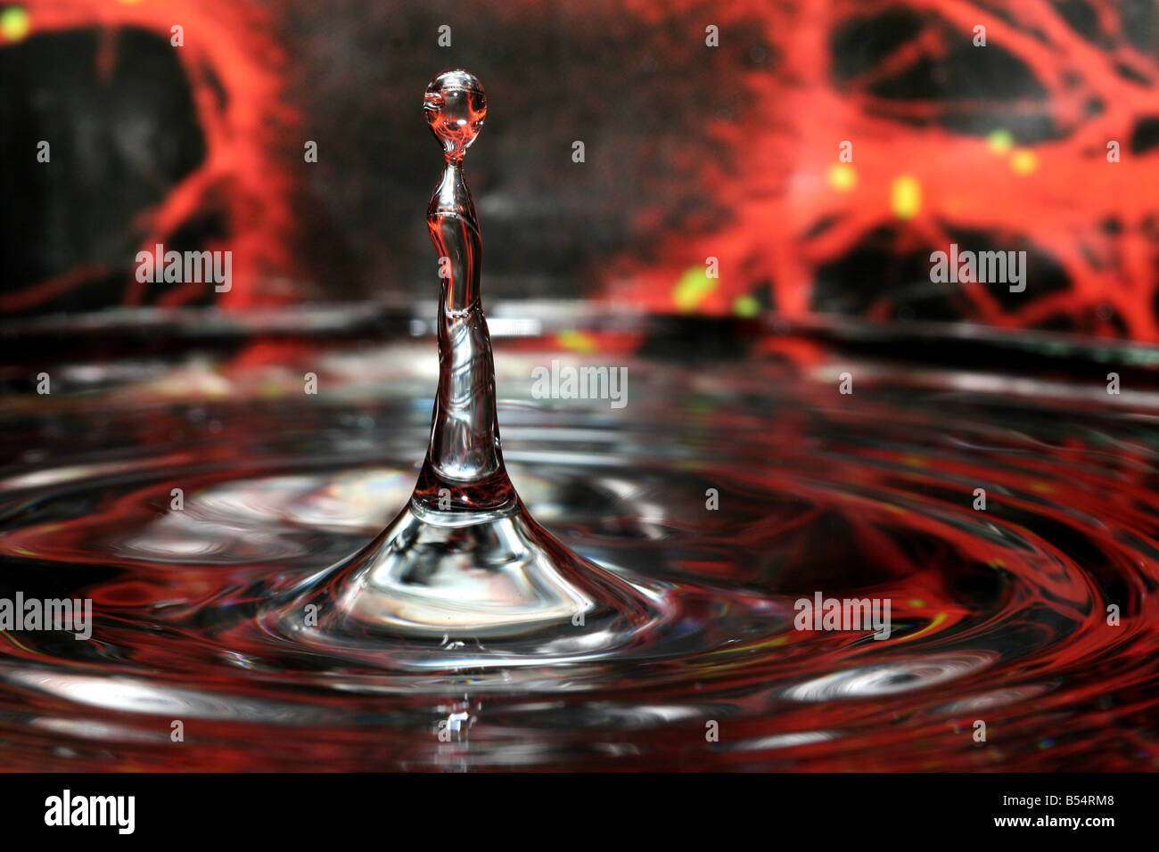 A drop of water creates a unique shape. Additional colors are reflected ...