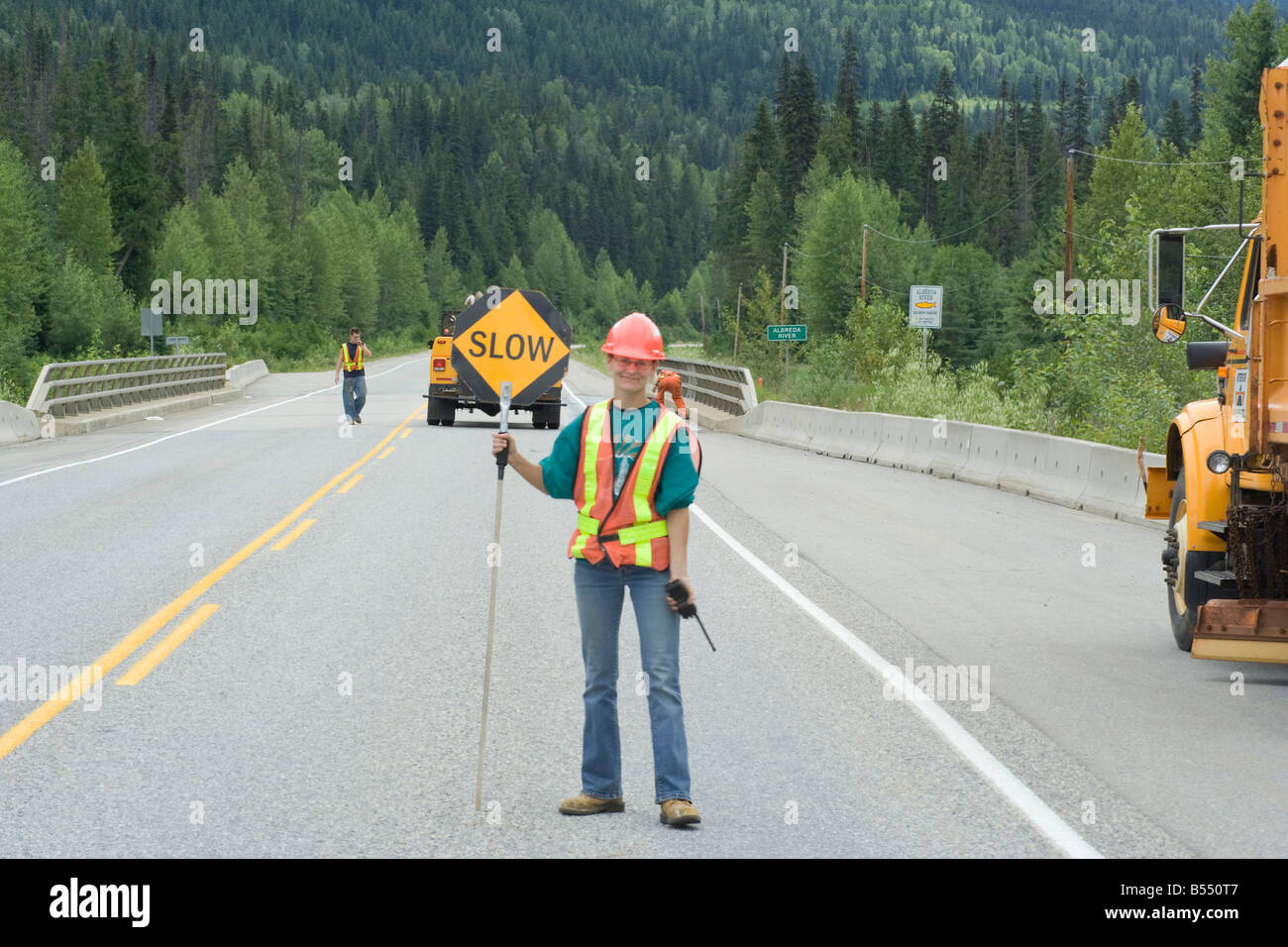 Female road worker holding Stop and Slow Sign Highway 18 in British ...
