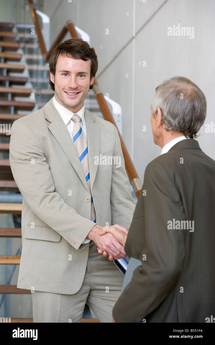 Two businessmen shaking hands on steps Stock Photo - Alamy