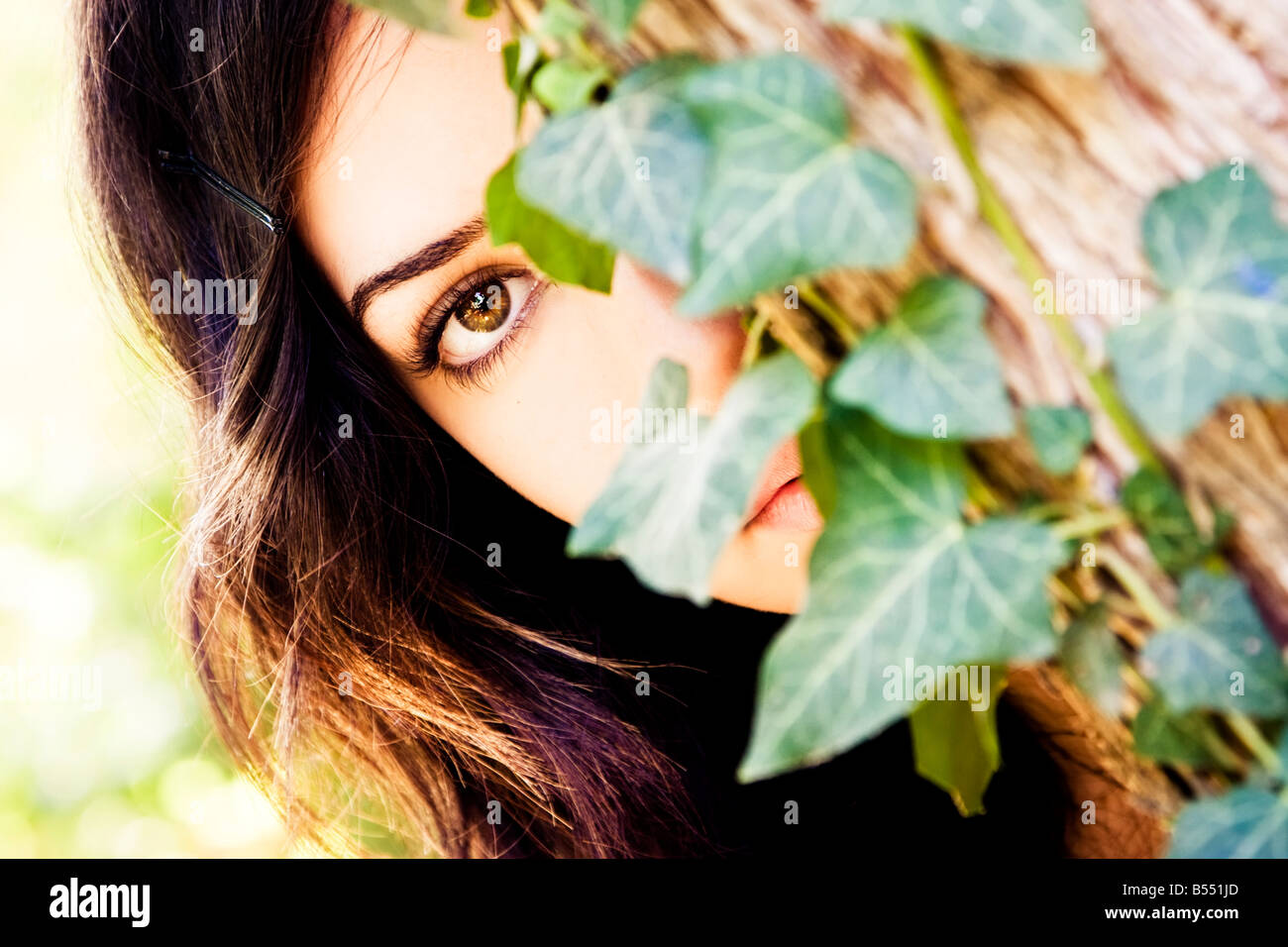 Young beautiful woman observing behind leaves Stock Photo - Alamy
