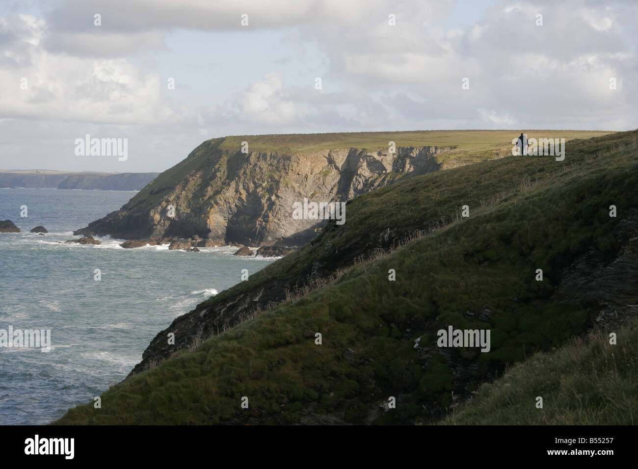 A young couple walk around Godrevy Point with Navax Point in the ...