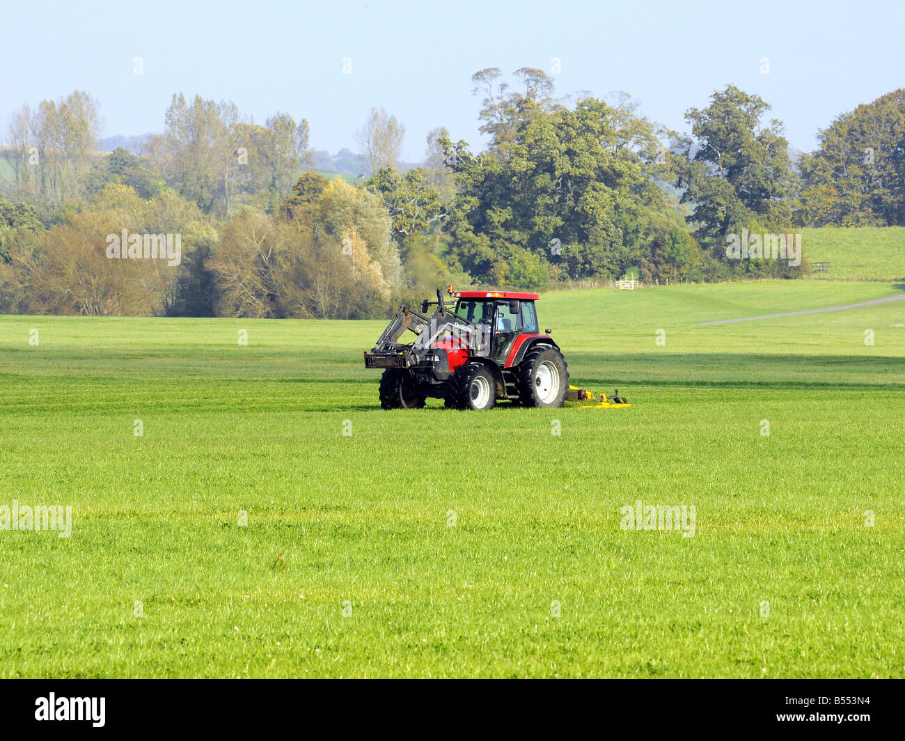 Red Farm tractor towing a large mowing machine Stock Photo - Alamy