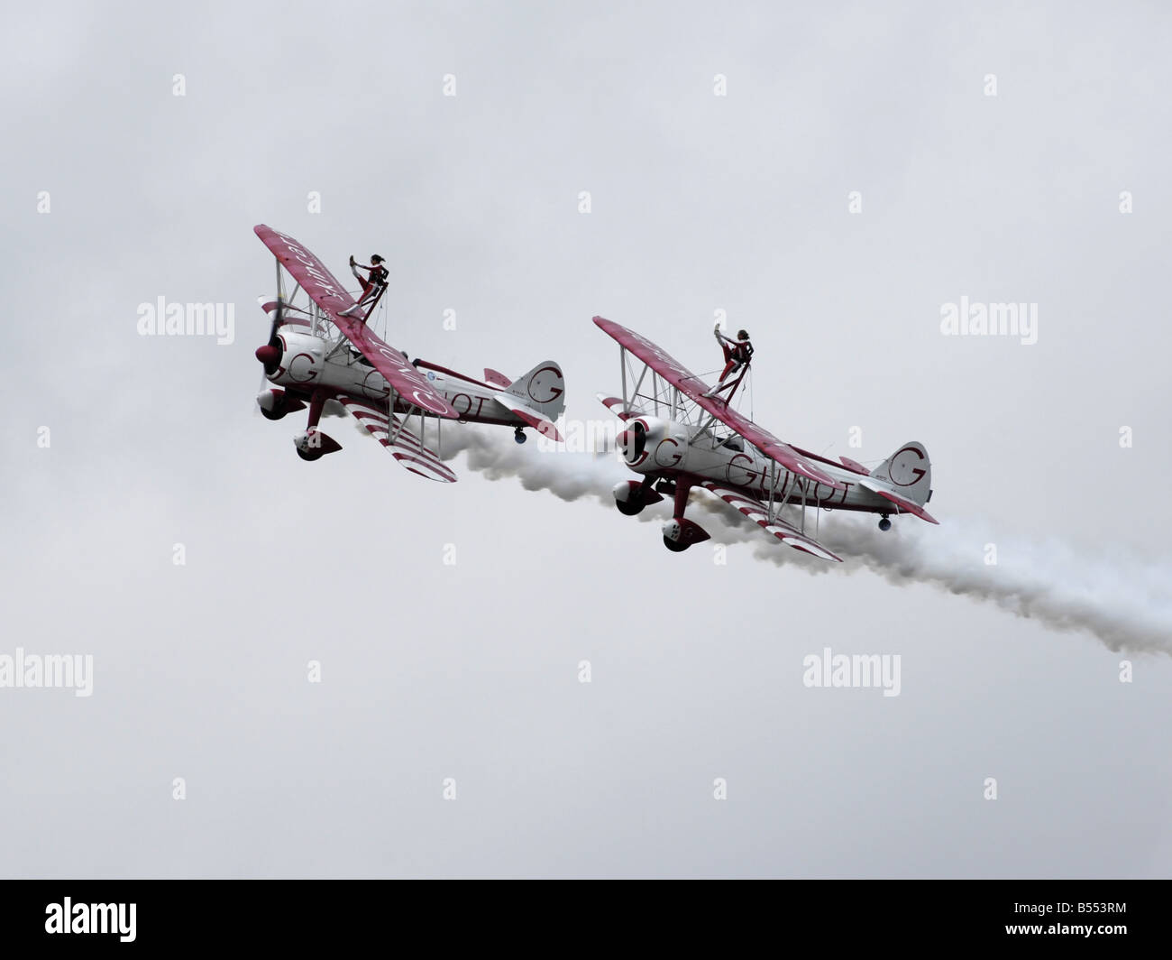 Stunt flying bi-planes with a female wing walker standing on the top ...