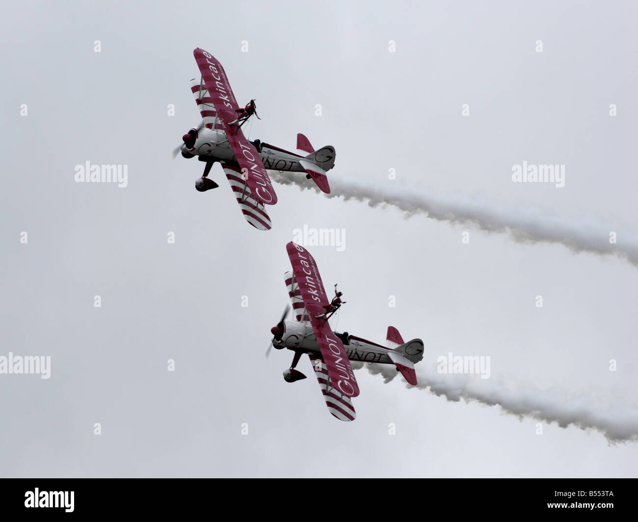 Stunt flying bi-planes with a female wing walker standing on the top ...