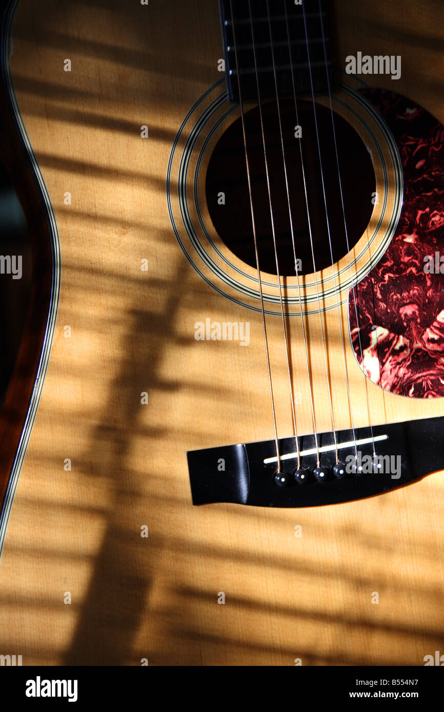 An acoustic steel string wooden guitar body sunlit with shadow lines ...