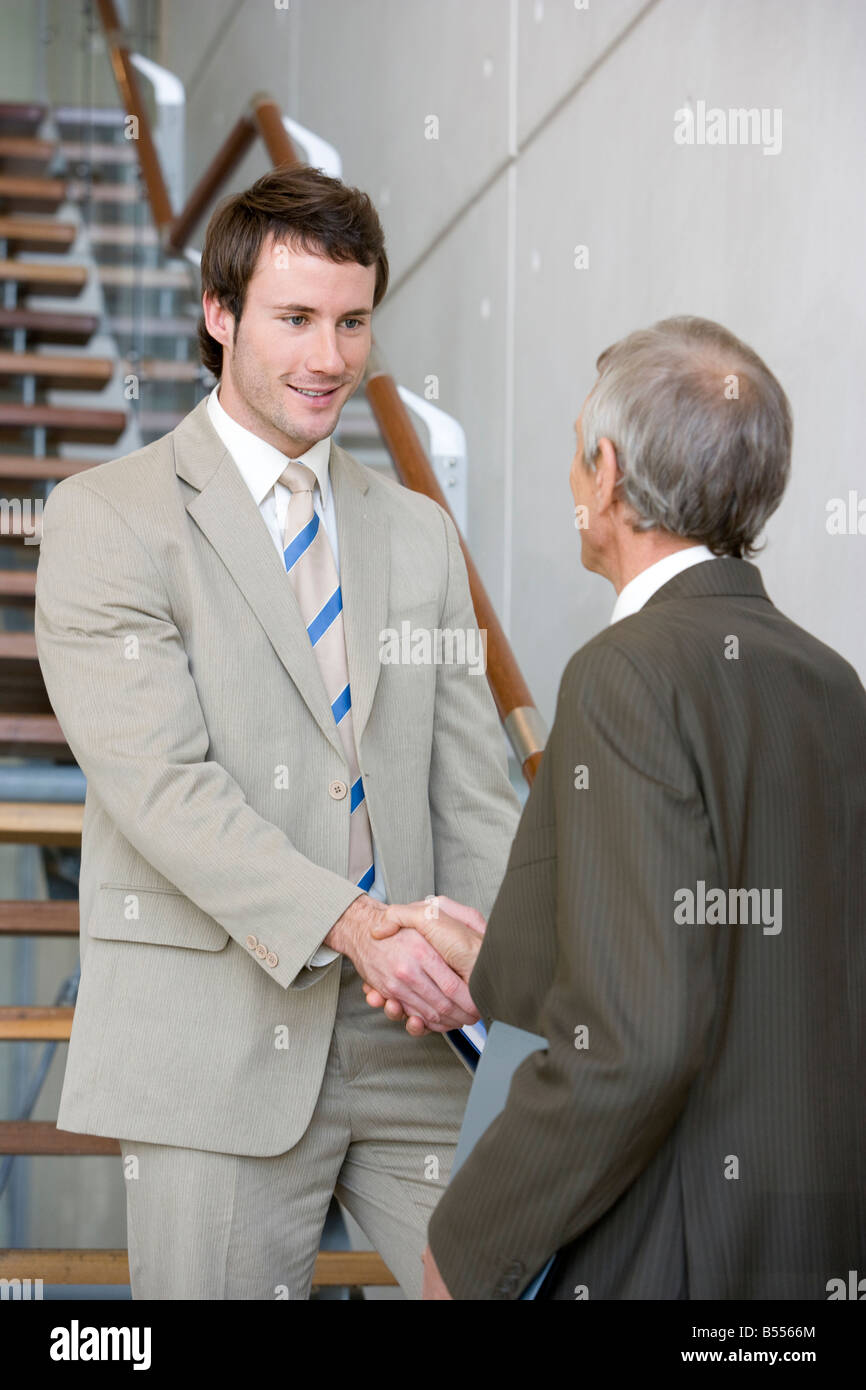 Two businessmen shaking hands on steps Stock Photo - Alamy