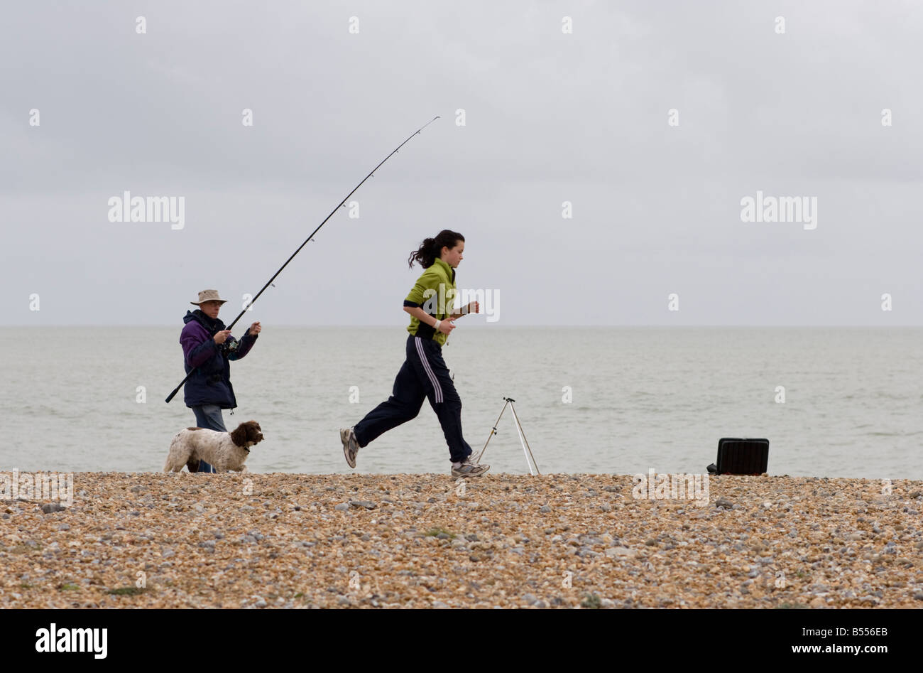 Girl jogging past beach angler and dog Stock Photo - Alamy