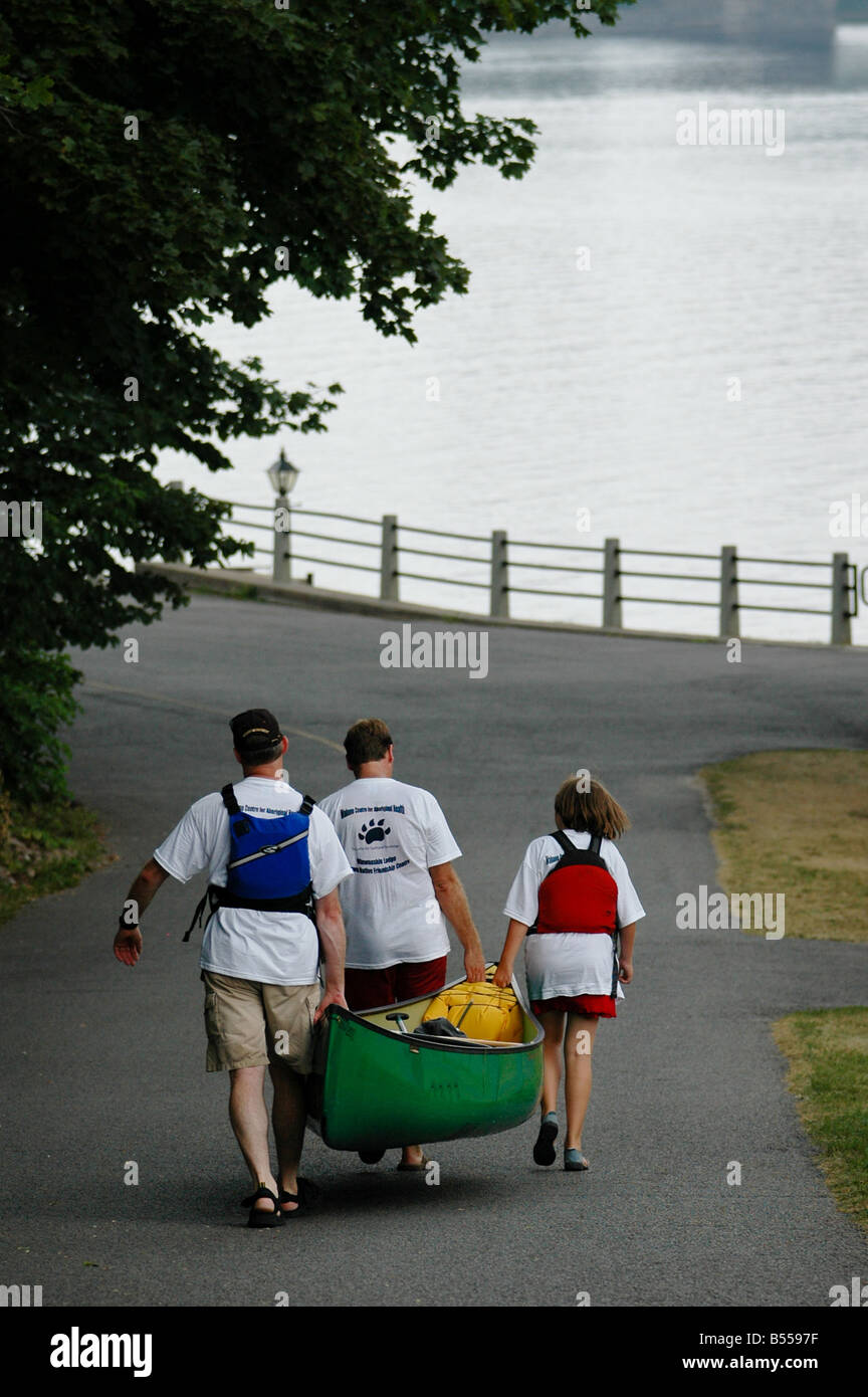 A team of three people carry a large canoe to the waterfront Stock ...