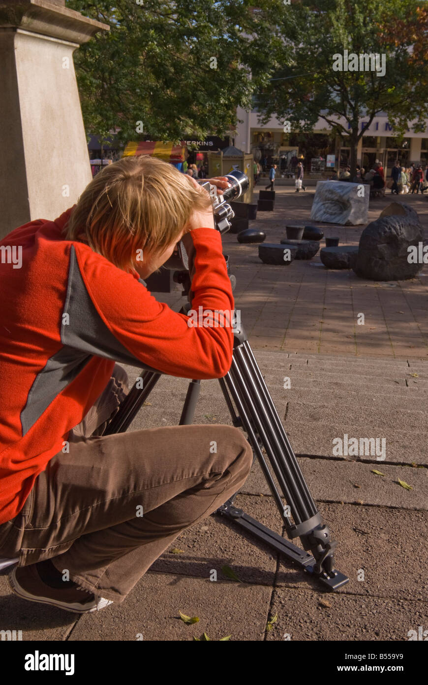 Young man using movie camera on large heavy duty tripod in Norwich ...