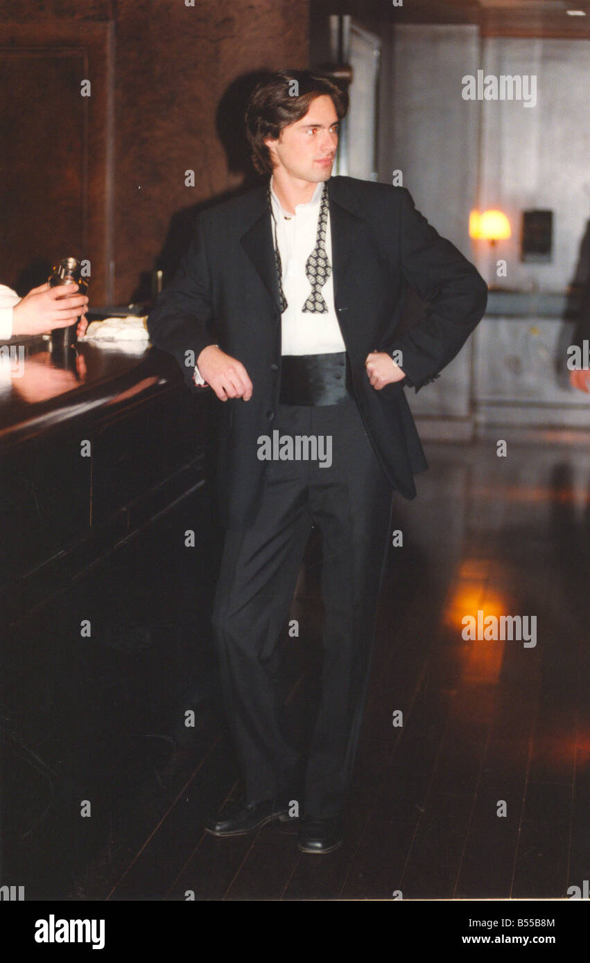 A young man posing in the latest suit waiting for his date to show up ...