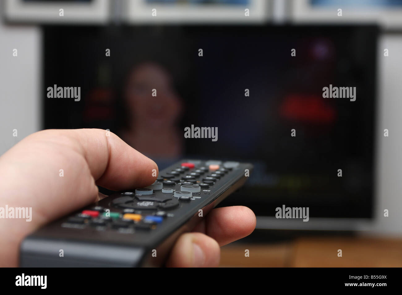 Human hand holding a remote control poined at flat screen tv Stock ...