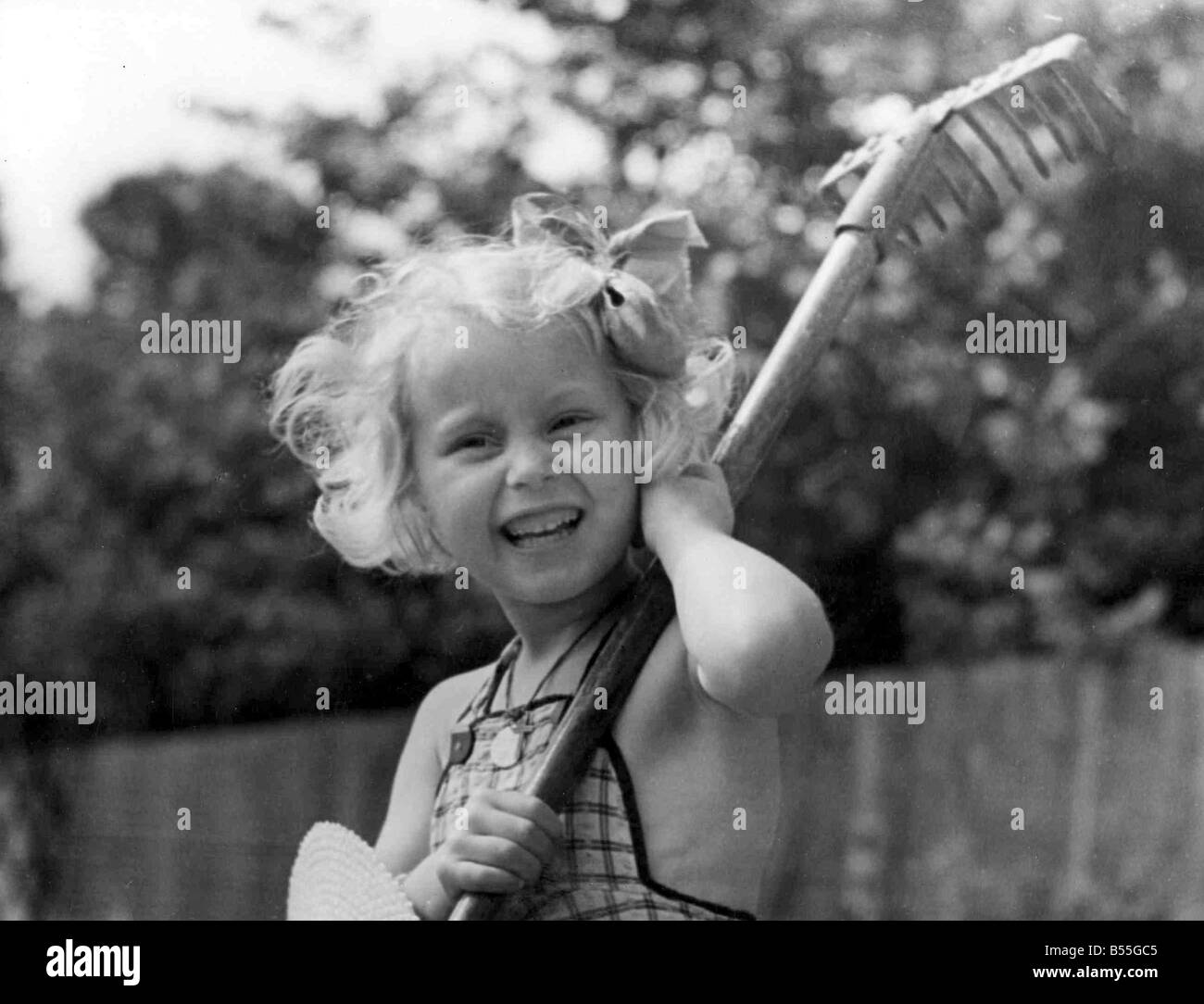 Young girl holding a rake in the back garden Circa 1945 P044440 Stock ...
