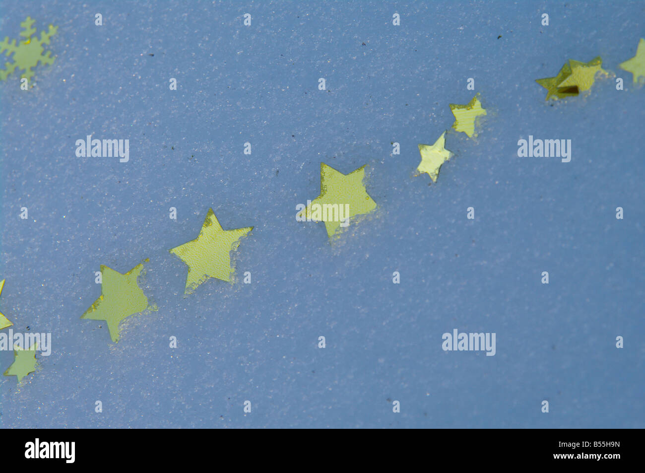 golden snow stars on a real snowy icy surface Stock Photo - Alamy