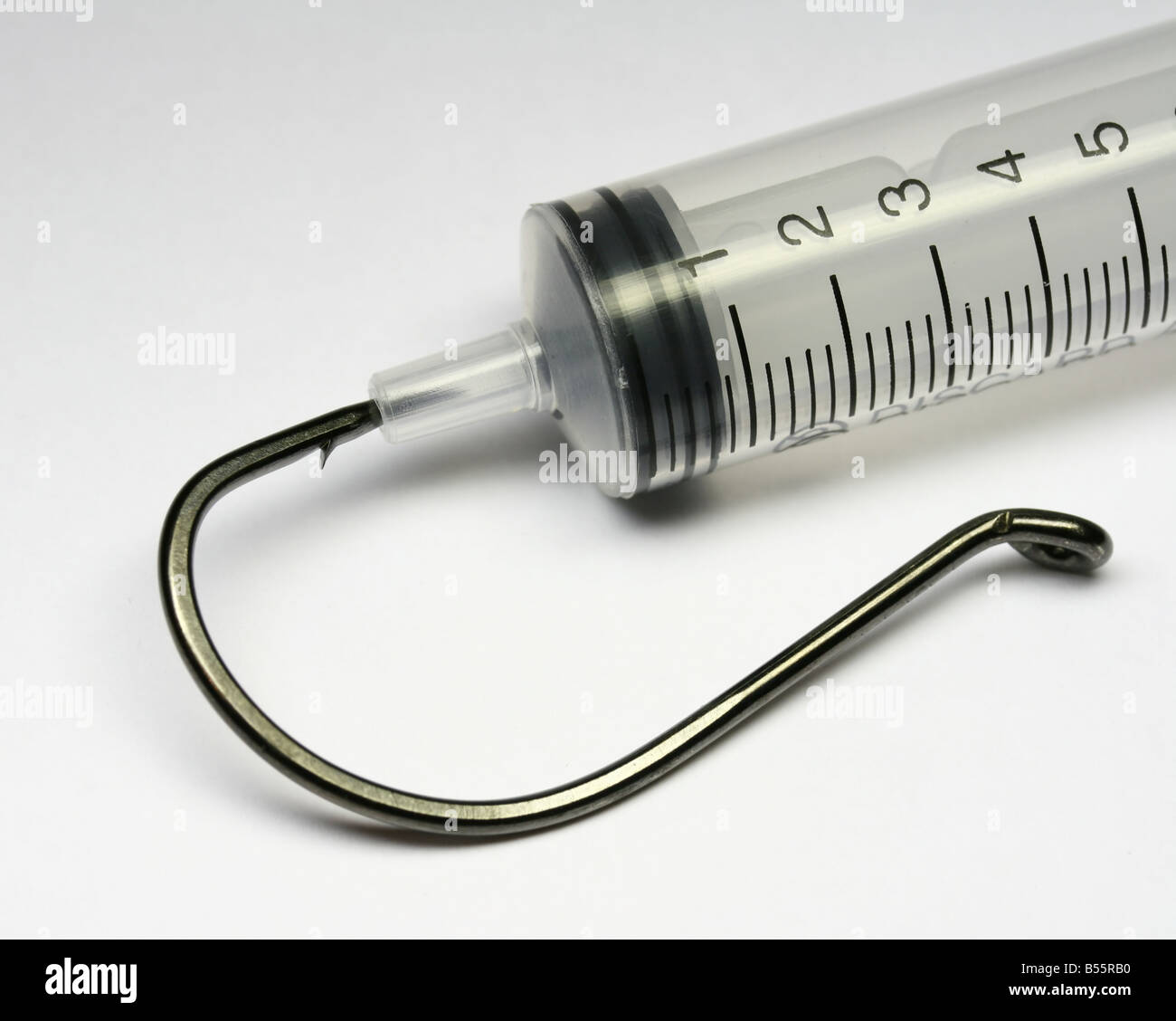 Close-up of fish hook and syringe on white background Stock Photo - Alamy
