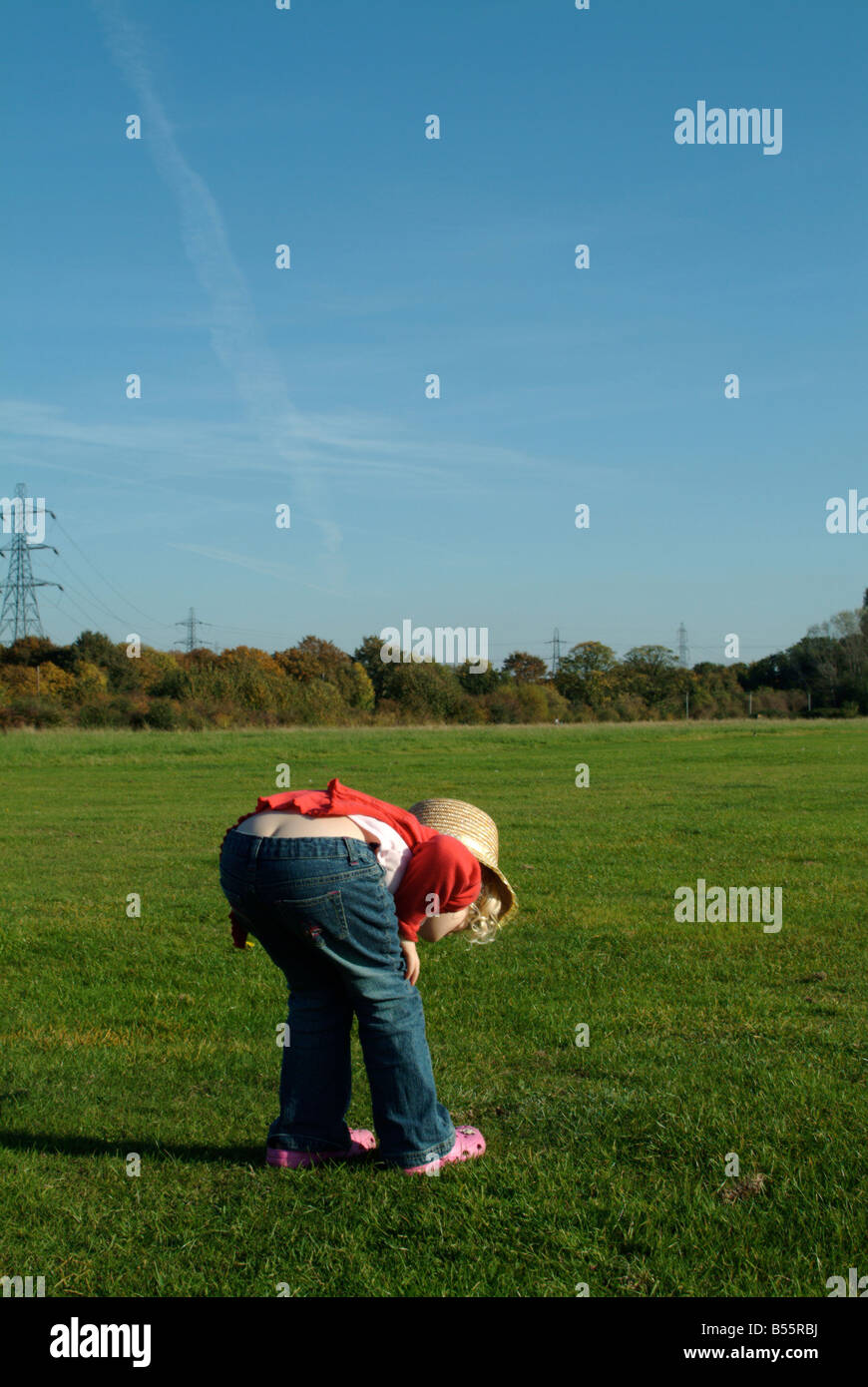 Little girl bending down in the countryside Stock Photo - Alamy