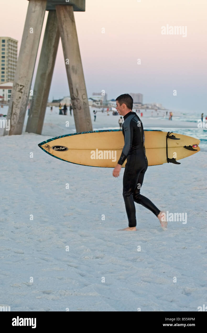 Surfer on the beach carrying surfboard done for the day on the water ...