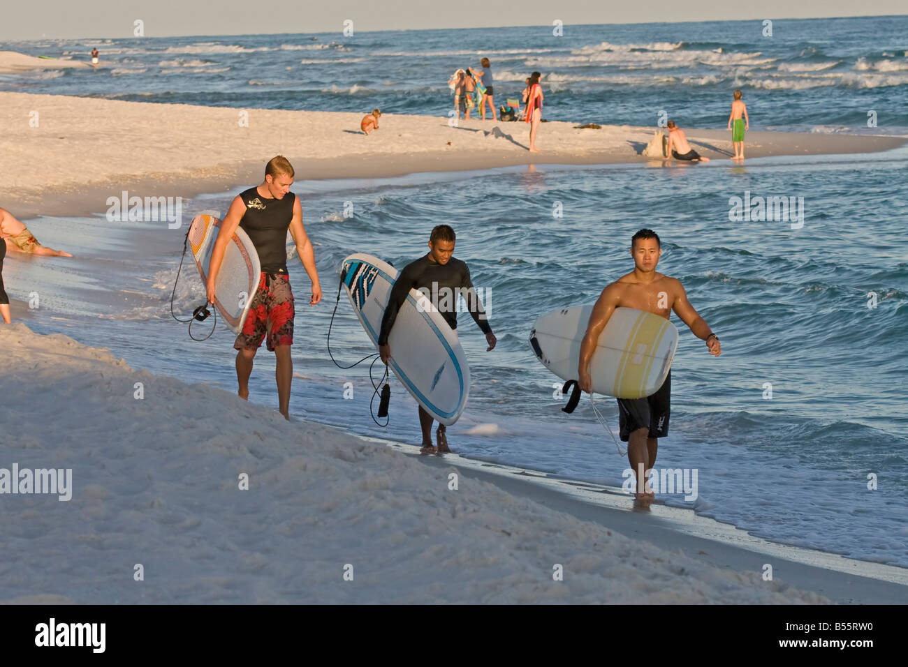 Three surfers carrying there surf boards down the beach Stock Photo - Alamy